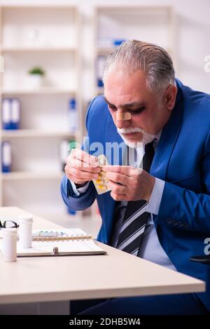 Old injured employee sitting in the office Stock Photo - Alamy