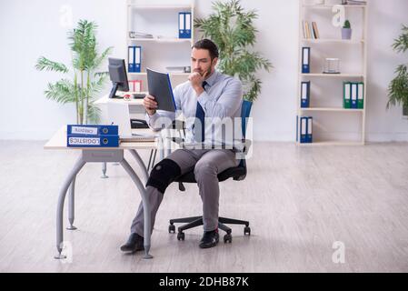 Young leg injured employee working in the office Stock Photo - Alamy