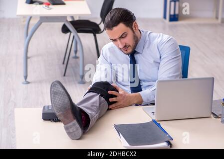 Young leg injured employee working in the office Stock Photo - Alamy