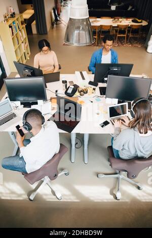 High angle view of group of programmers discussing new software in team ...