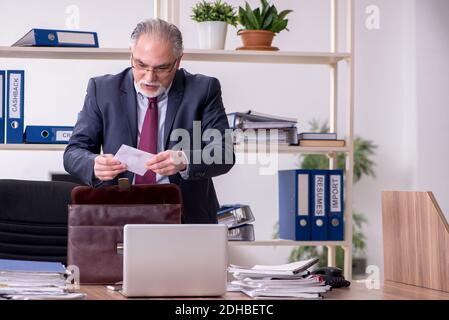 Old male employee unhappy with excessive work at workplace Stock Photo ...