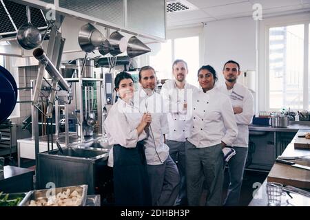Portrait of group chefs standing together in commercial kitchen at ...
