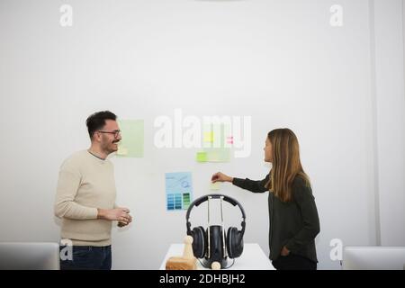 Young businesswoman with over ear headphones listening music from her ...