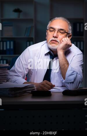 Old male employee working late at the workplace Stock Photo - Alamy