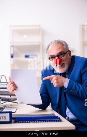 Old businessman clown working in the office Stock Photo - Alamy