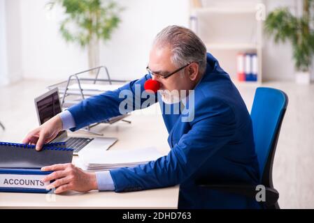 Old businessman clown working in the office Stock Photo - Alamy