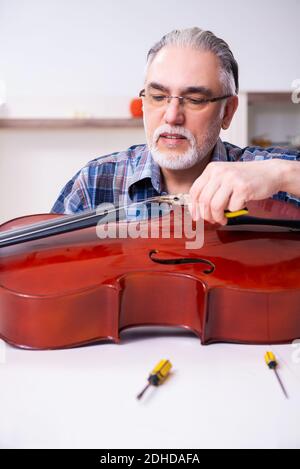 Old repairman repairing musical instruments at workplace Stock Photo ...