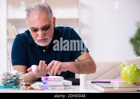 Old injured man in budget planning concept Stock Photo - Alamy