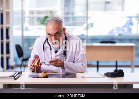 Old doctor cardiologist working in the clinic Stock Photo - Alamy