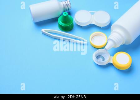 Containers with contact lenses, solutions and tweezers on color ...