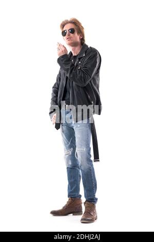 Stylish rebellious biker or rocker young man looking down smoking ...