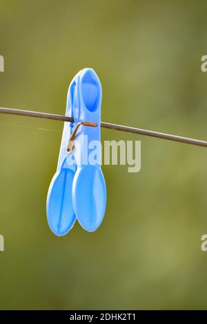 A single green clothes peg or pin on a washing line, against a cloudy ...