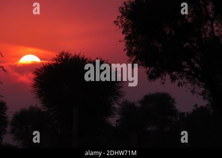 The sunset view of a sun half hidden behind the dark cloud over Gulf of ...