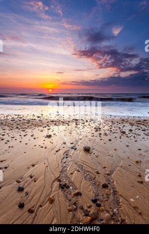 The sun just above the sea horizon creating a sunrise / sunset with a ...