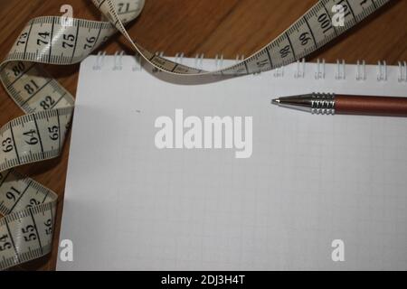 A notebook with measurement tape and a pen. Planning a diet healthcare ...