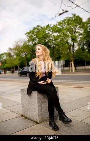 young smiling austrian female in rose dress sitting in city Stock Photo ...