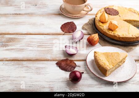 Autumn onion pie decorated with leaves and cup of coffee on white ...