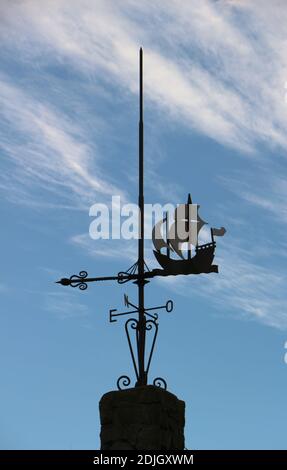 Tall weather vane with a galleon on top of a stone structure in the ...