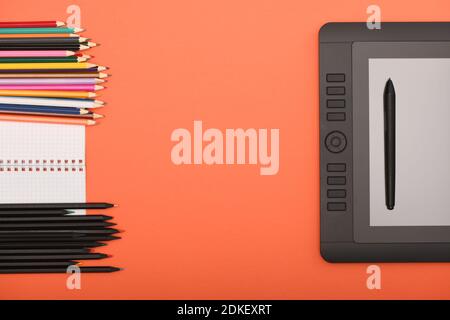 Graphic monitor stylus on orange color table. Black tablet computer ...