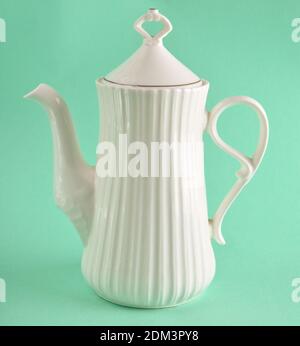 Blue and white ornate teapot with a teacup on a wooden table lit warmly ...