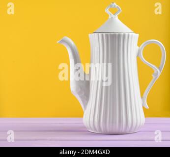 Blue and white ornate teapot with a teacup on a wooden table lit warmly ...