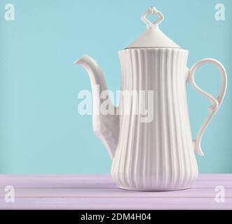 Blue and white ornate teapot with a teacup on a wooden table lit warmly ...