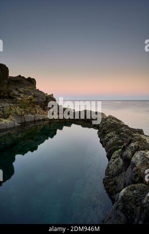Spectacular scenery of calm sea surrounded by hills in overcast weather ...