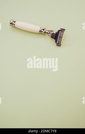 A vertical shot of a beige and black razor isolated on a green ...