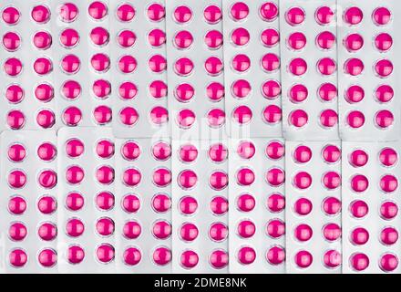Round pink tablets pills in blister packs on white background with copy ...