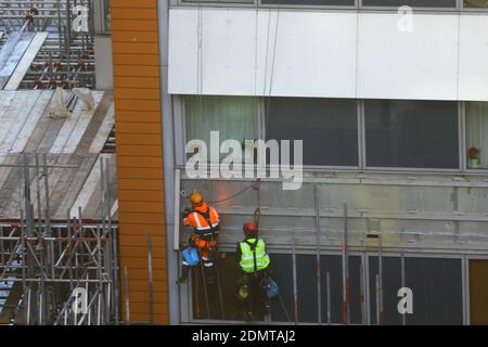 Workmen remove the cladding from the facade of a block of flats in ...