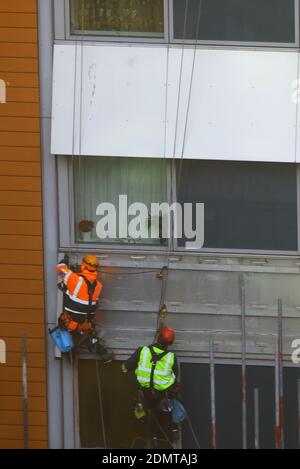 Workmen remove the cladding from the facade of a block of flats in ...