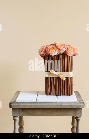 Floral arrangement with roses and cinnamon sticks stands on the table ...