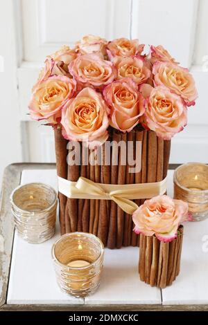 Floral arrangement with roses and cinnamon sticks stands on the table ...