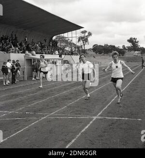 1960s, historical, outside on a cinder track, two young boys competing ...