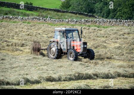 Farmer rowing up hay with an old Fergie tractor and acrobat Stock Photo ...