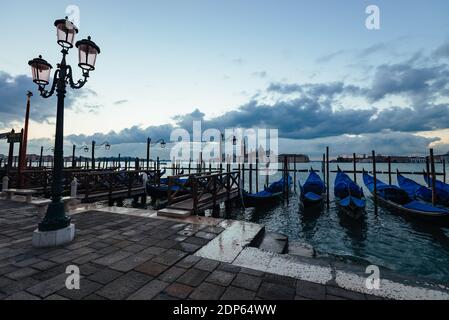 A row of moored gondole at the Traghetto Gondola Molo jetty with views ...