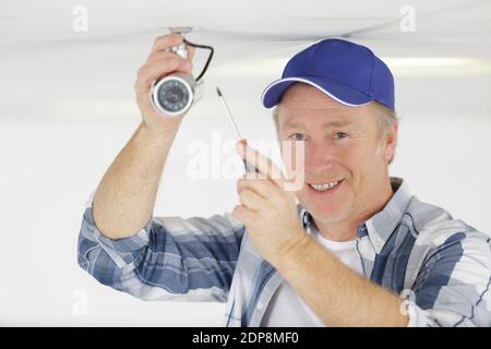 senior contractor installing overhead cctv camera Stock Photo - Alamy