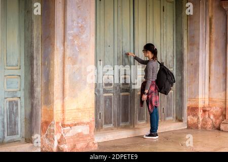 young girl knocking on front door of house using metal door knocker ...
