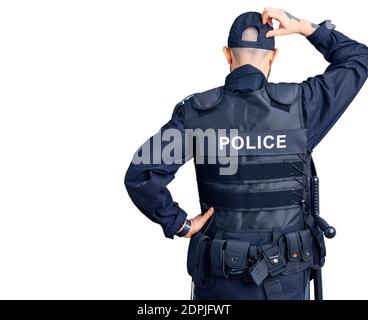Young handsome man wearing police uniform peeking in shock covering ...