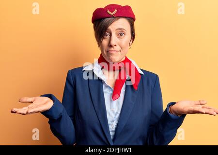 Young confused flight attendant shrugging shoulders, showing unsure ...