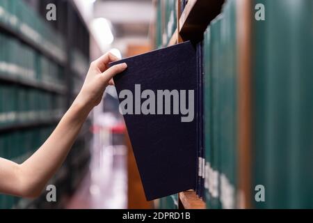 Hand pulling a book off the shelf Stock Photo - Alamy