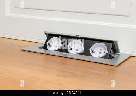 Three hidden sockets on a wooden kitchen countertop close-up, copy ...