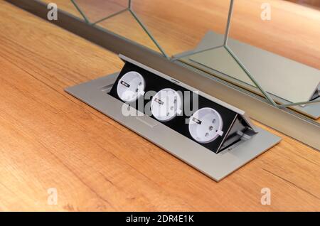 Three hidden sockets on a wooden kitchen countertop close-up, copy ...