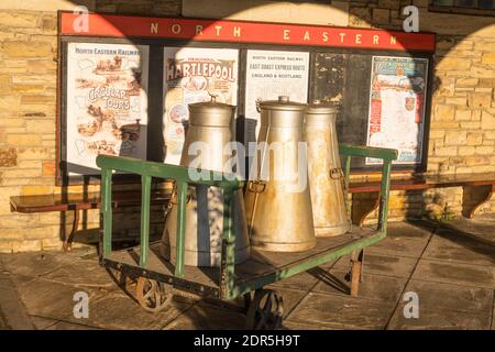 Old milk churns on a milk churn stand at a farm entrance Pembrokeshire ...