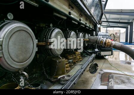 Fuel tanker unloading at a service station, with two hoses connected ...