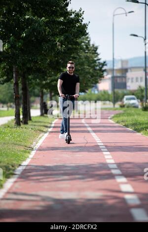 young strong man riding electric kick scooter copy space Stock Photo ...