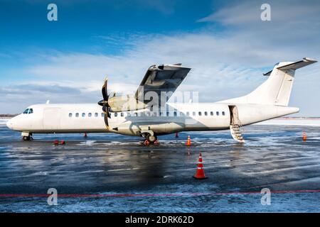 White passenger turboprop aircraft on the airport apron in cold winter ...