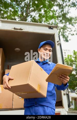 Delivery man carrying cardboard box Stock Photo - Alamy