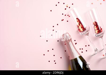 Glasses with heart shaped confetti on pink background with space for ...