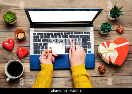 Girl holds debit card, chooses gifts, makes purchase, laptop, coffee ...